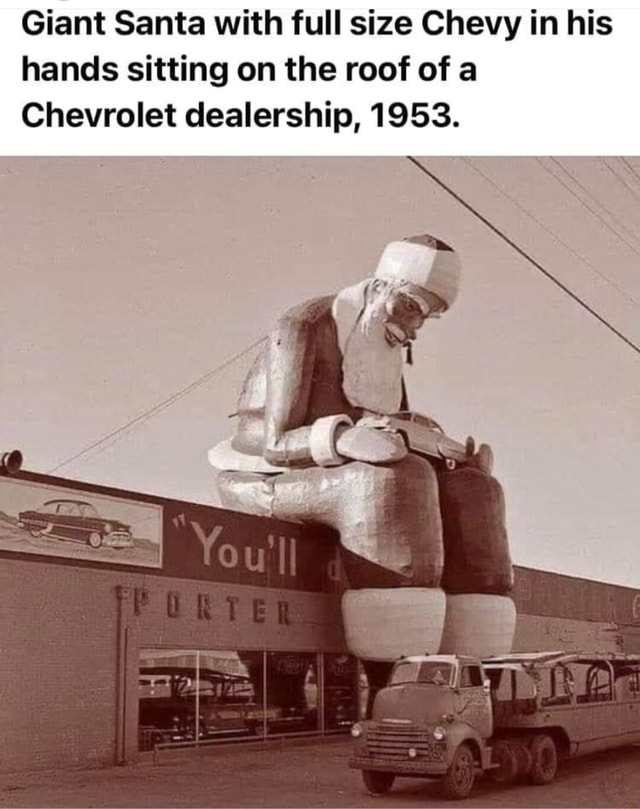 Giant Santa with full size Chevy in his hands sitting on the roof of a ...